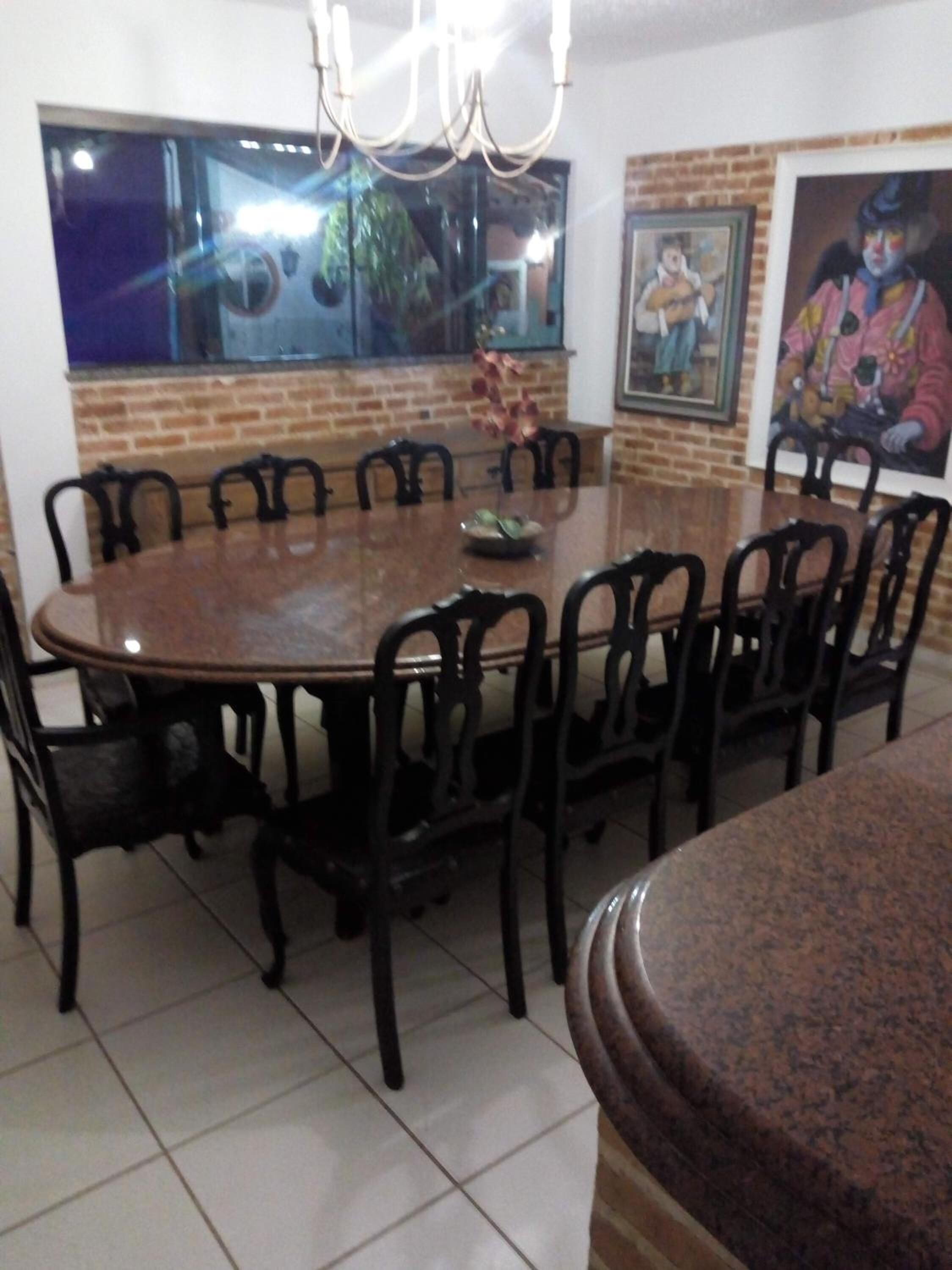 Uma sala de jantar com uma mesa redonda e cadeiras, um lustre e obras de arte nas paredes.