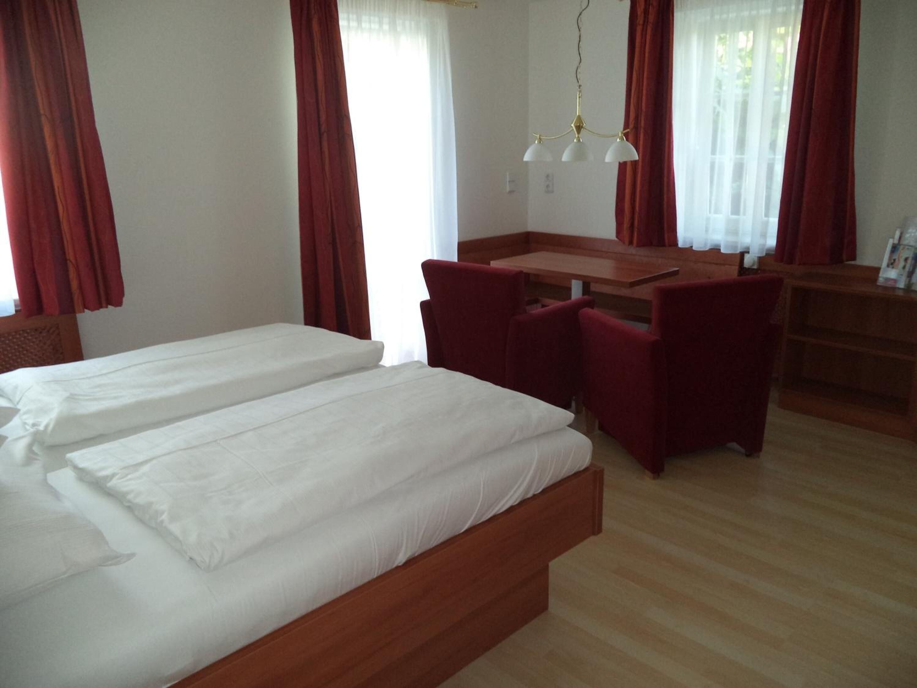 Quarto com duas camas, uma escrivaninha e uma cadeira.