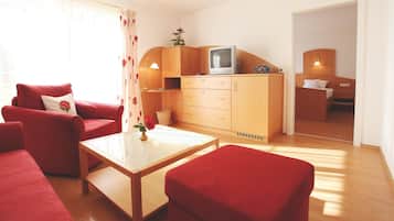 Um espaço compacto com cozinha americana, um sofá vermelho, uma mesa pequena e uma cama.
