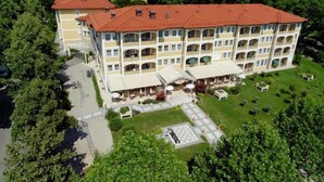 Um hotel de vários andares com telhado vermelho, varandas e um pátio com mesas ao ar livre.