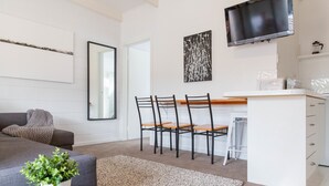 Uma sala de estar moderna com um sofá, uma mesa de centro com uma planta, um tapete e uma área de jantar com cadeiras e uma mesa.