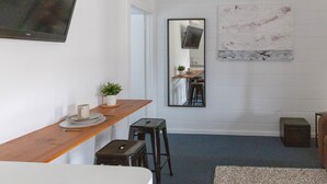 Quarto moderno com escrivaninha de madeira, espelho, obra de arte em mármore e uma pequena planta em vaso.