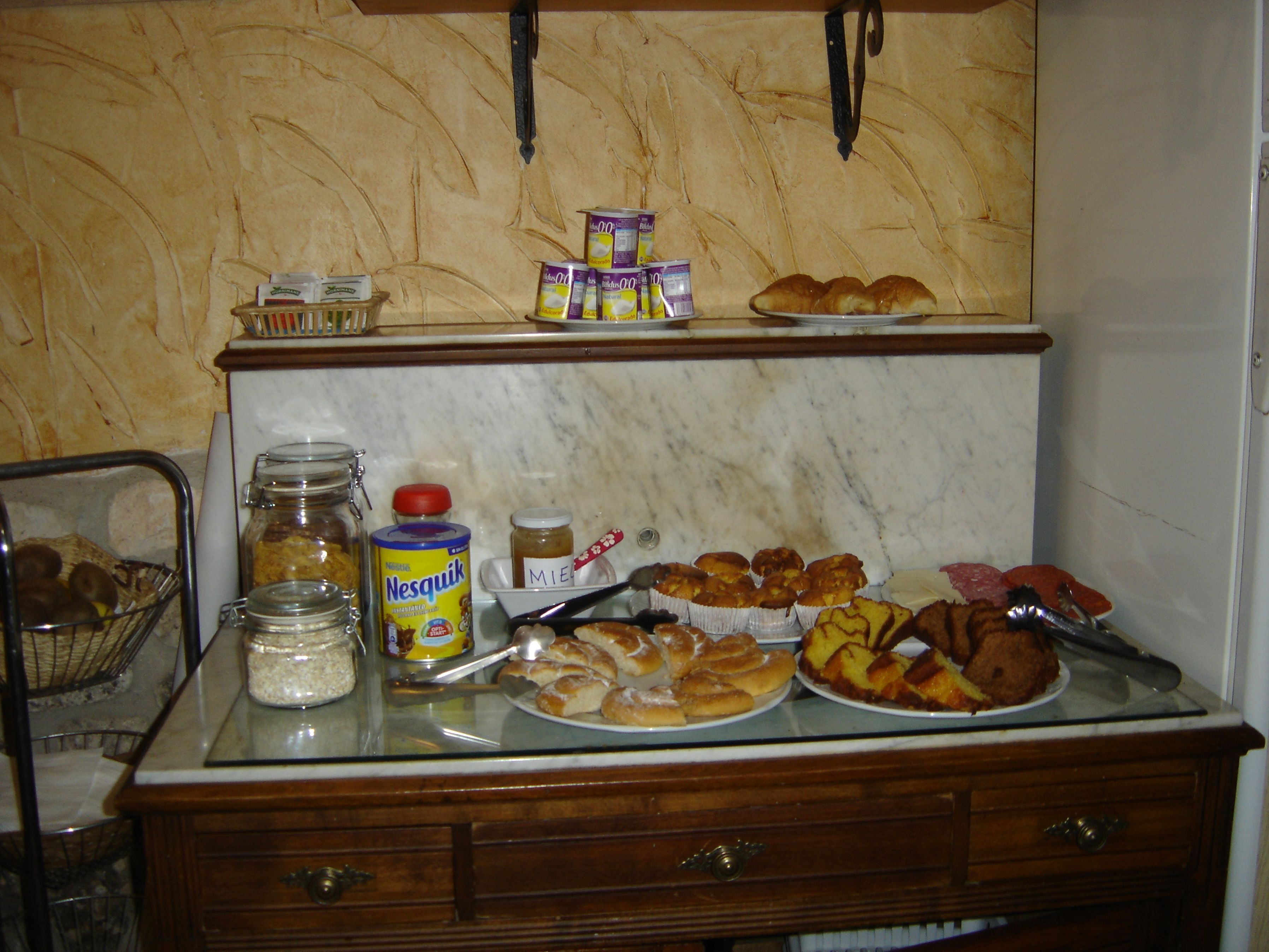 Uma bancada de cozinha com diversos alimentos e acompanhamentos, incluindo potes, garrafas e pratos de pastelaria.