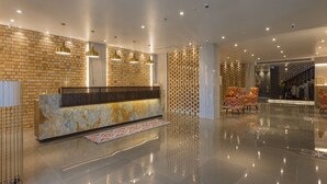 Um lobby moderno com uma recepção de mármore, paredes de tijolo e piso lustroso.