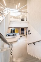 Interior moderno com escadas para um segundo andar, balcão de recepção e placas de sinalização para os portões A e D a F.