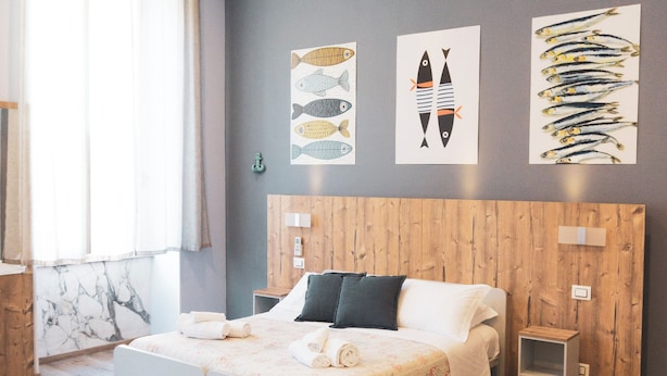 Um quarto moderno com cabeceira de madeira, cama com roupa de cama branca e obras de arte nas paredes.