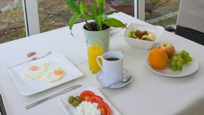 Uma mesa de café da manhã com pratos de comida, uma xícara de café e um vaso de planta.