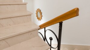 Uma escadaria com degraus de mármore e corrimão de madeira.