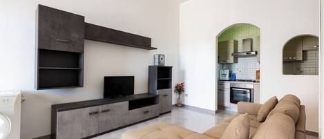 Uma sala de estar moderna com um sofá, uma TV de tela plana e um painel de entretenimento embutido.