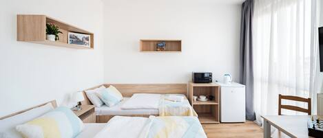 Quarto de hotel com duas camas, uma escrivaninha, micro-ondas e um pequeno frigorífico.