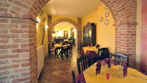 Um restaurante com arcos de tijolo, paredes amarelas e mesas preparadas para refeições.