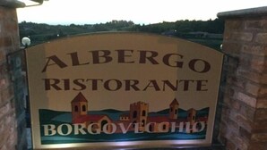 Placa para Albergo Ristorante com representação de um edifício e paisagem.