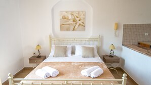 Quarto de hotel com cama, duas mesas de cabeceira, telefone fixado na parede e uma obra de arte emoldurada acima da cama.
