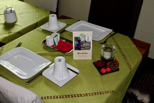 Uma mesa de jantar bem posta, com pratos brancos, talheres e um cardápio.