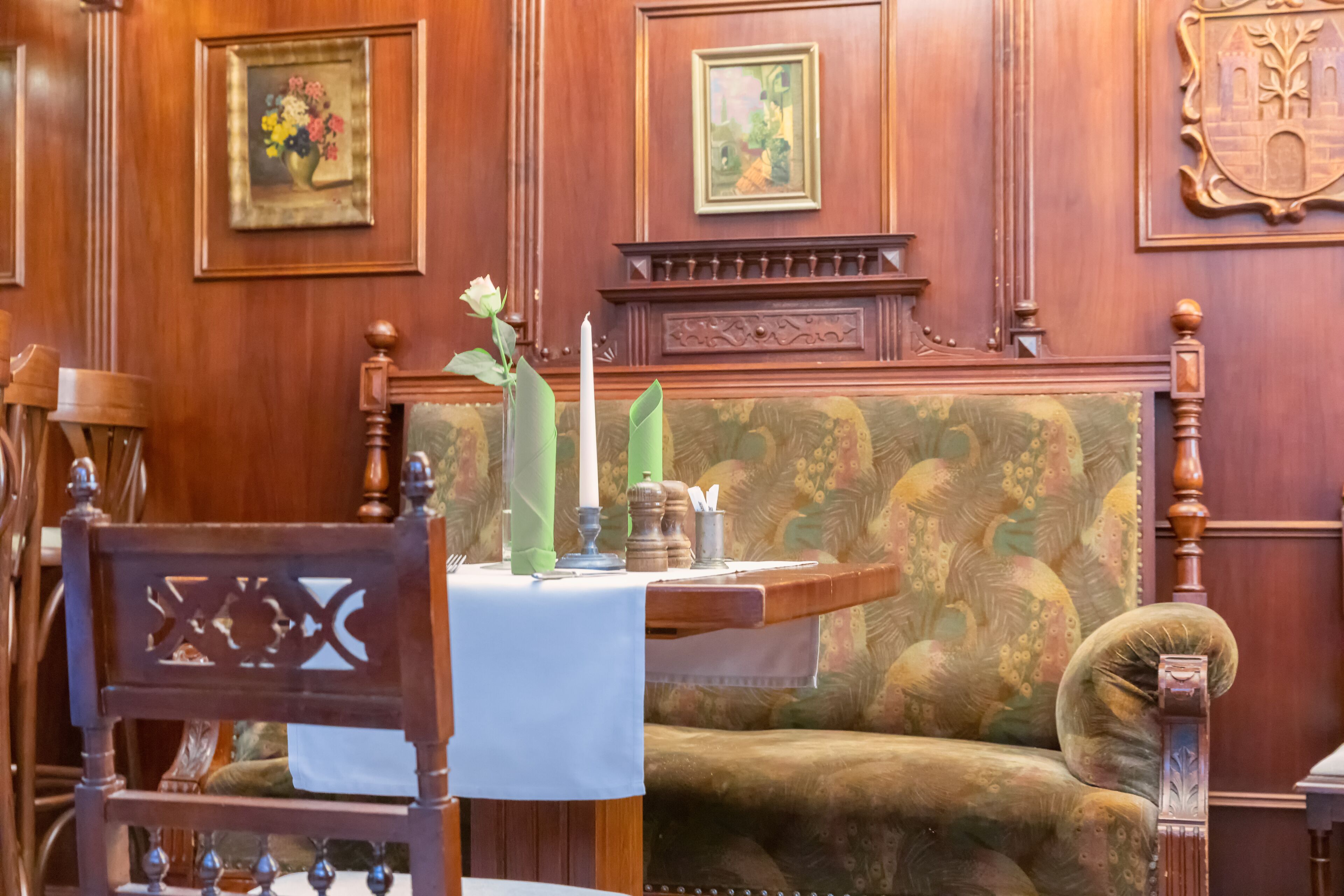 Um quarto com um banco de madeira, uma mesa com toalha branca e um sofá estampado com flores.