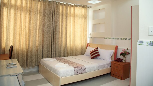 Quarto bem arrumado com cama, mesa de cabeceira e uma cadeira.
