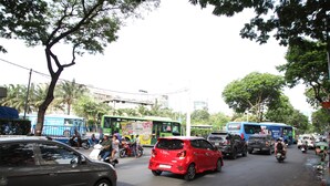Ruas movimentadas com vários veículos, incluindo carros e ônibus, e pessoas em motocicletas.