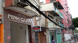 Um edifício com a placa 'Hotel Minh Quang' e uma motocicleta estacionada na frente.
