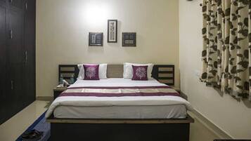 Quarto bem arrumado com cama, mesas de cabeceira e guarda-roupa.