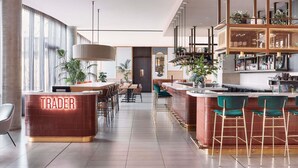 Uma área de bar moderna com um balcão identificado como 'TRADER', arranjos de assento e vista da área do bar.