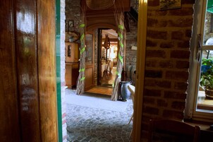 Interior rústico com soalho de pedra, vigas de madeira e parede de tijolo.