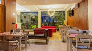 Um restaurante com interior moderno, incluindo um sofá vermelho, mesas de jantar e luminárias pendentes.