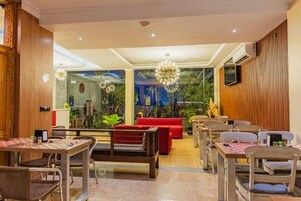 Um restaurante com interior moderno, incluindo um sofá vermelho, mesas de jantar e luminárias pendentes.