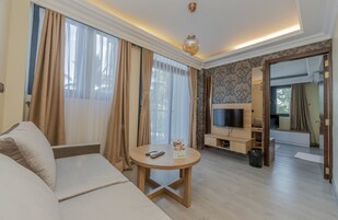 Uma sala de estar moderna com um sofá, uma mesa redonda de madeira, uma televisão e um papel de parede estampado.