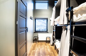 Quarto compacto com beliches, janela com vista para as montanhas e radiador.