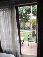 Quarto com vista para uma varanda, uma cadeira e uma mesa lá fora.