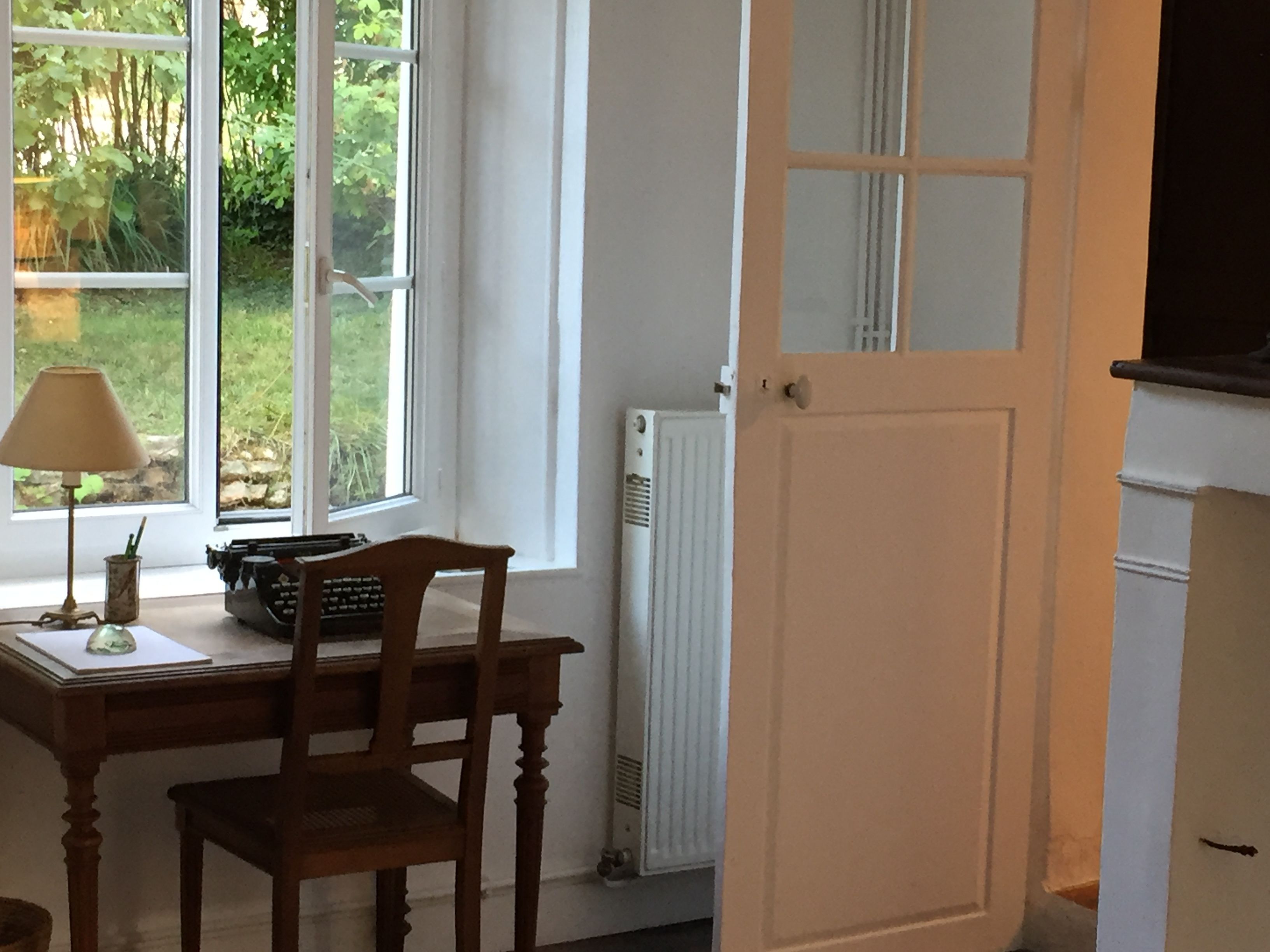 Quarto com escrivaninha de madeira, luminária e radiador.