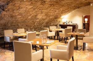 Restaurante com paredes de pedra e mesas preparadas para refeições.