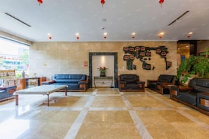 Um saguão de hotel com piso xadrez, área de estar e um mural com um mapa.