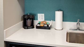 Uma bancada de cozinha com uma cafeteira, um lenço de papel e um dispensador de toalhas de papel.