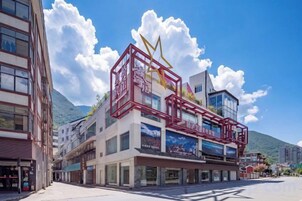 Um edifício moderno com uma estrutura vermelha marcante, grandes janelas e céu claro.