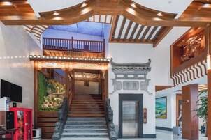 Um saguão de hotel com uma escadaria, um portão tradicional e uma varanda.