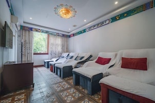 Quarto com uma fileira de camas, um armário de madeira e um chão estampado.