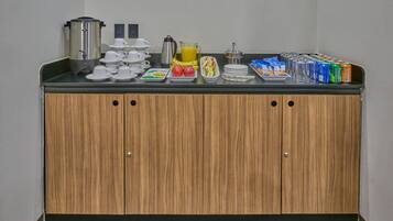 Uma mesa de pequeno-almoço com café, sumo e diversas opções de comida.
