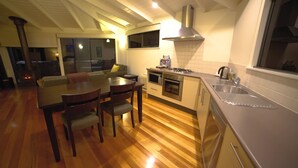 Uma cozinha moderna com soalho de madeira, uma área de refeições com mesa e cadeiras, e um forno embutido.
