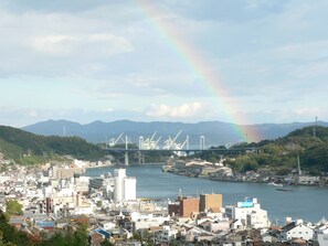Paisagem costeira com um rio, prédios e um arco-íris.