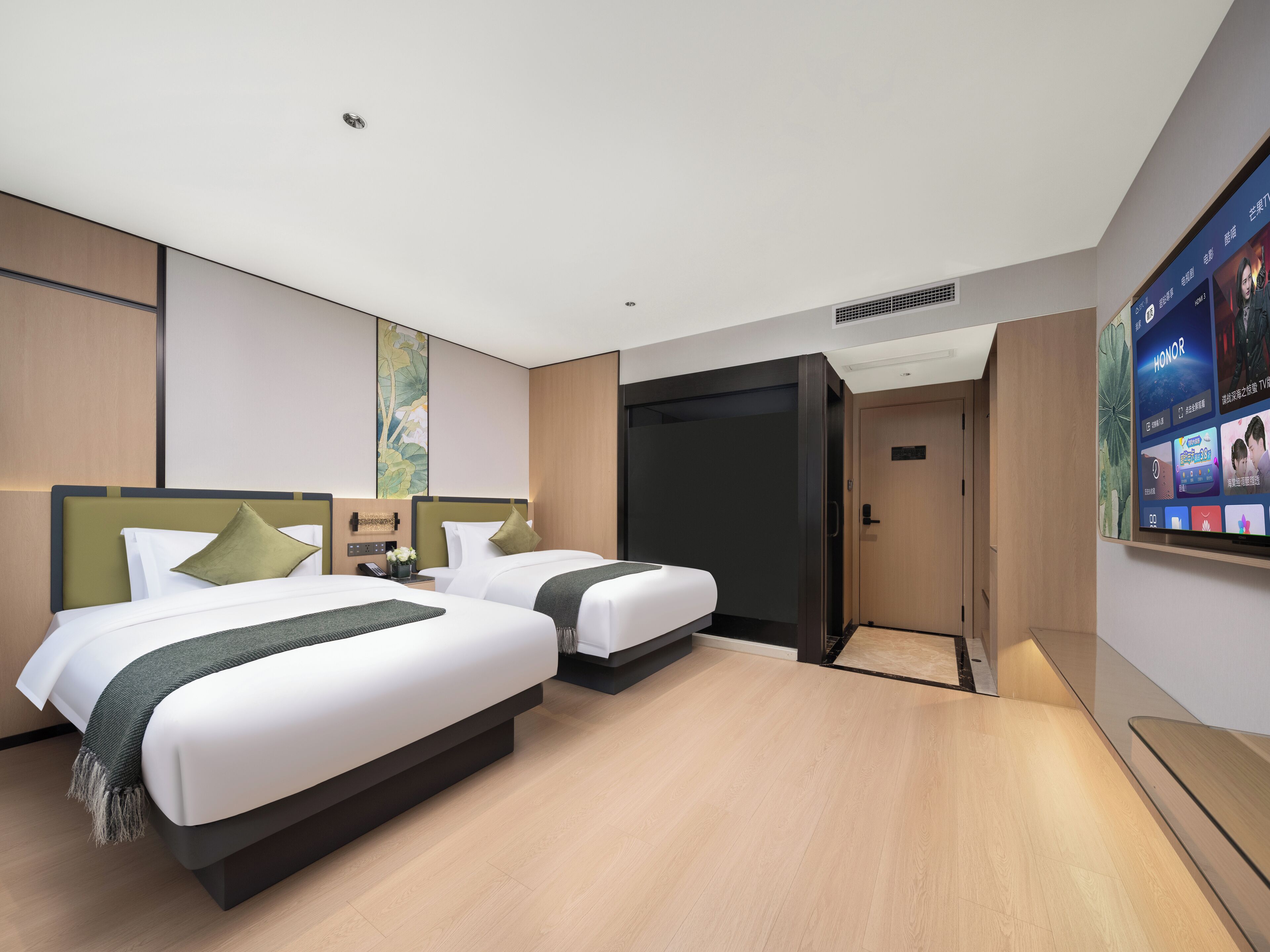 Quarto de hotel moderno com duas camas, uma televisão de tela plana na parede e piso de madeira.