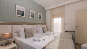 Quarto de hotel com uma cama grande, uma mesa de cabeceira com abajur e uma porta à direita.