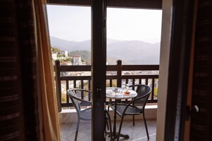 Varanda com mesa e cadeiras, proporcionando vista para edifícios e montanhas ao longe.
