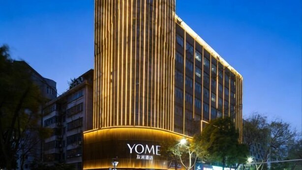 Um hotel YOME com design moderno, caracterizado por linhas verticais e sinalização iluminada.
