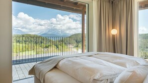 Quarto com uma grande janela, uma cama e vista para as montanhas.
