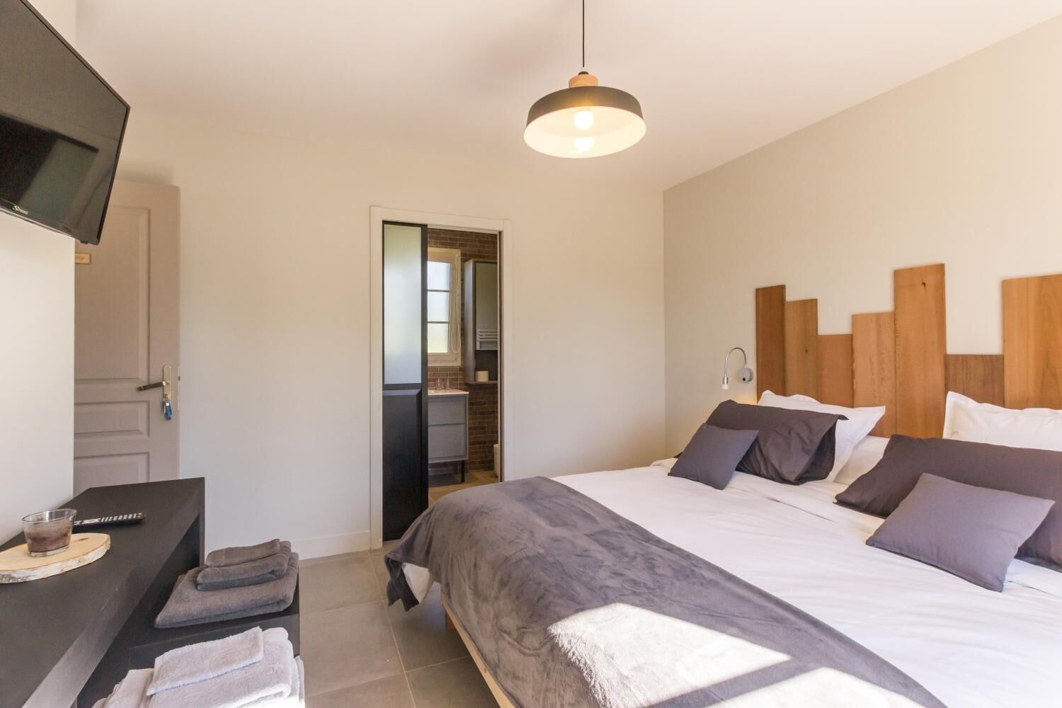 Quarto com cama, televisão, mesa de cabeceira e espelho.