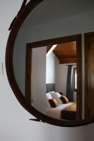 Quarto com cama, almofadas e teto de madeira.