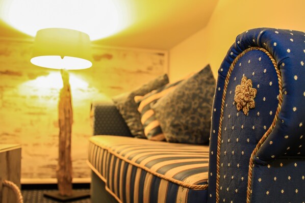 Um quarto aconchegante com sofá, almofadas estampadas e uma luminária.