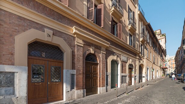Uma rua de paralelepípedos flanqueada por edifícios históricos, com grandes portas de madeira e janelas em arco.