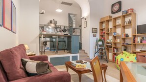 Uma sala de estar com um sofá vermelho, uma mesa de centro de madeira e uma estante.